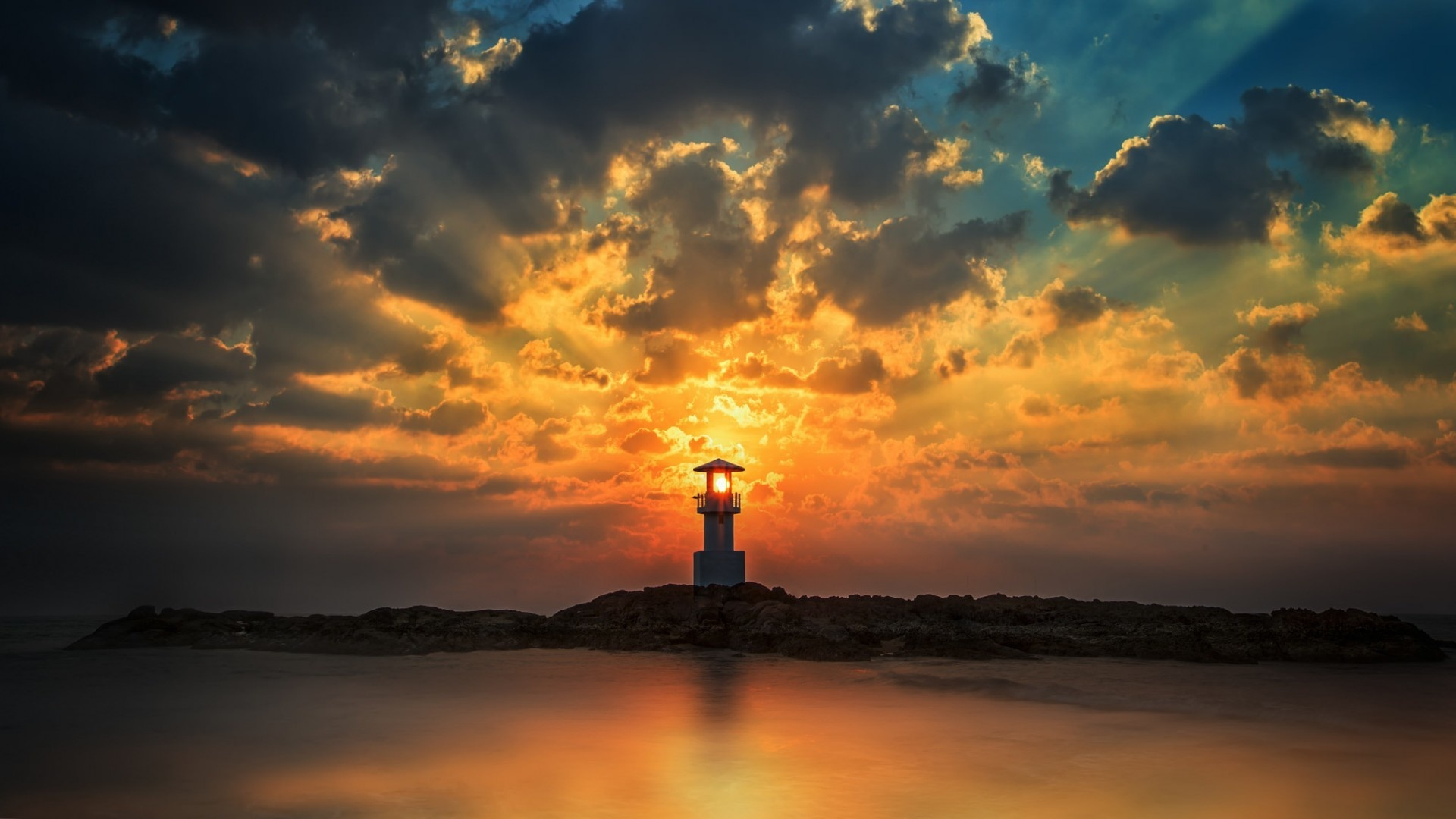 Sunlit Lighthouse at Ocean's Edge: Stunning Sunset HD Wallpaper
